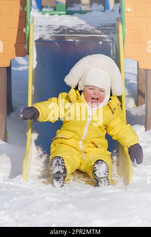 Der kleine Junge fährt auf einer Rutsche und spielt auf einem ...