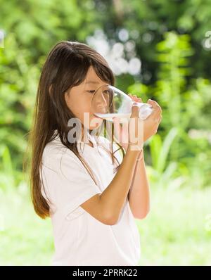 Eine süße junge asiatische Frau trinkt ein Glas Milch, während sie ihr ...
