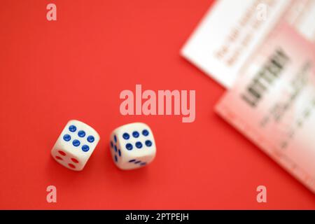 Rote Lotterie-Ticket mit Würfel liegt auf rosa Glücksspiel-Blätter mit ...