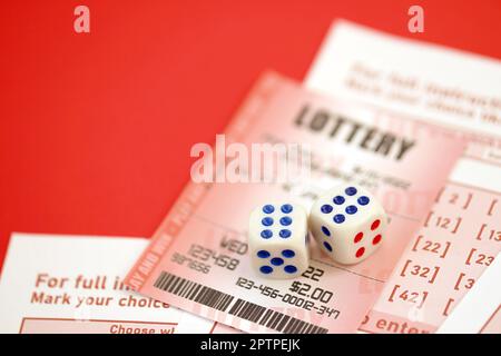 Rote Lotterie-Ticket mit Würfel liegt auf rosa Glücksspiel-Blätter mit ...