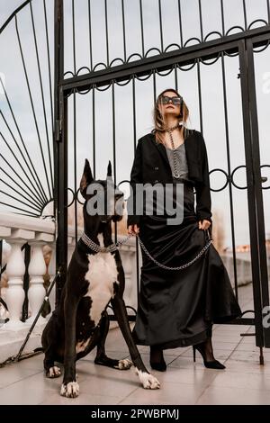 Eine Frau geht mit ihrer Dogge in einer urbanen Umgebung spazieren und ...