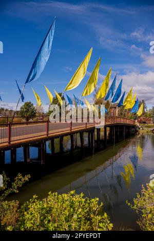Eine Fußgängerbrücke mit Flaggen über dem Deschutes River im Old Mill ...