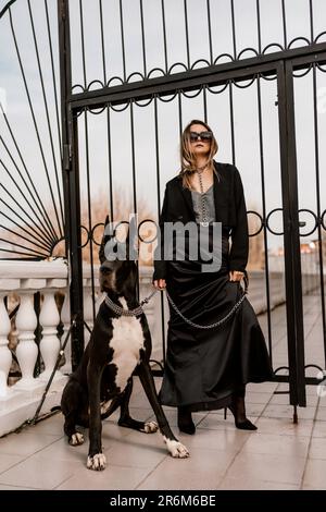 Eine Frau geht mit ihrer Dogge in einer urbanen Umgebung spazieren und ...