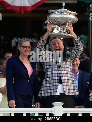 Trainer Jena Antonucci, left, hoists up the August Belmont Trophy ...
