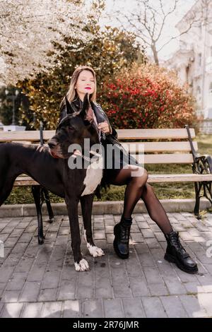 Eine Frau geht mit ihrer Dogge in einer urbanen Umgebung spazieren und ...