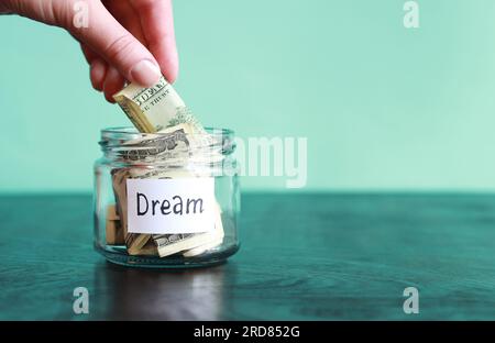 Sparen Sie Geld für einen Traum. Die Hand einer Frau steckt einen ...