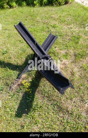 Anti-Panzer-Metallbefestigungen und Igel auf grünem Gras, Schienenstücke, die zusammengeschweißt ...