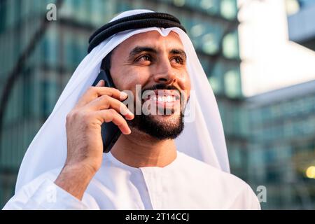 Arabischer Mann aus dem Nahen Osten, der in der Stadt traditionelle emiratische Kandora-Kleidung ...