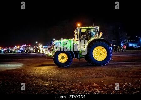 Lichterfahrt - grüner mit weihnachtlichen Lichterketten geschmückter Traktor fährt auf einem ...