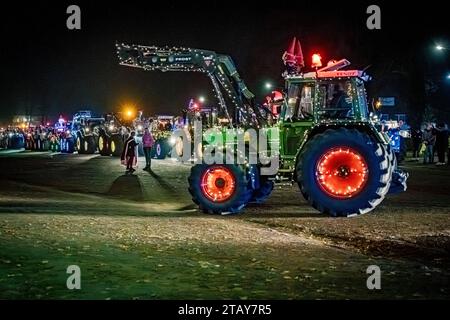Lichterfahrt - grüner mit weihnachtlichen Lichterketten geschmückter Traktor fährt auf einem ...