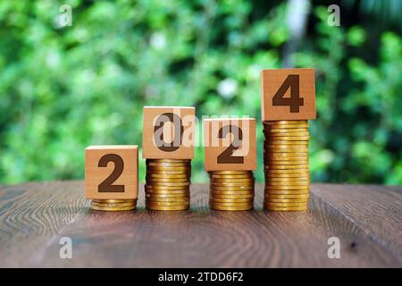 Stapeln Sie Münzen auf Holzblock Jahr 2024 als Geschäfts- und ...