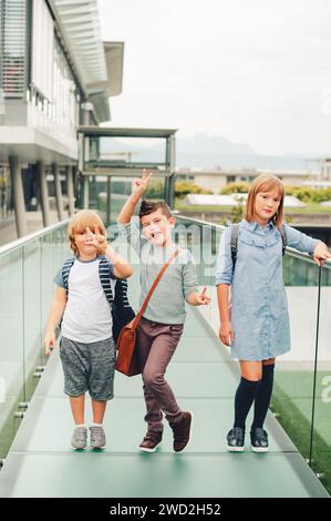 Gruppe von 3 lustigen Schulkindern, die sich im Freien ausgeben und Rucksäcke tragen. Back-to ...