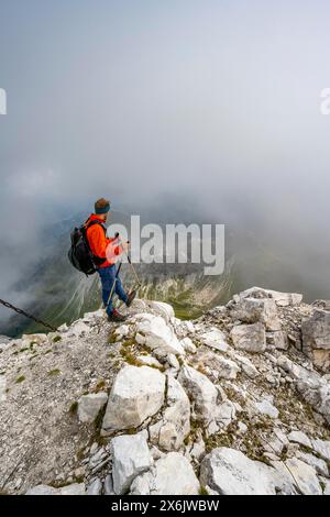 Bergsteiger auf einem felsigen schmalen Gipfelgrat, bewölkter ...