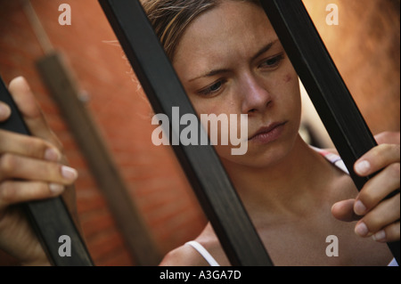 Eine weibliche Gefangene hinter Gittern in einem Frauengefängnis. Bild nach Modell gestellt ...