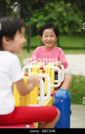 Zwei Mädchen sitzen auf einer Wippe auf dem Spielplatz Stockfotografie ...
