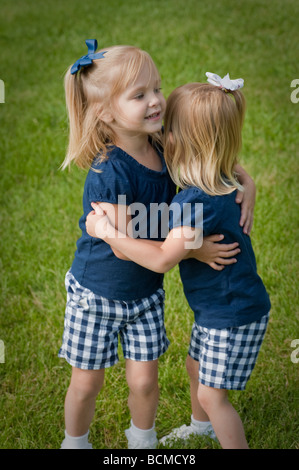 Hübsche kleine Zwillingsschwestern posieren. Eine zeigt die andere Seite nach vorne ...