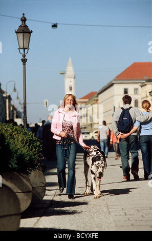 Eine Frau geht mit ihrer Dogge in einer urbanen Umgebung spazieren und ...