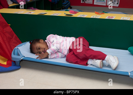 4 Jahre alte Kindergarten Mädchen liegend auf einem Feldbett während ...
