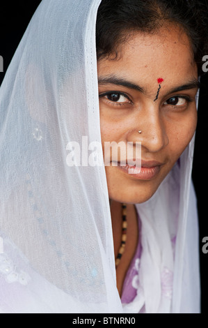 Eine hübsche Inderin mit lächelndem Gesicht, das die Haare berührt ...