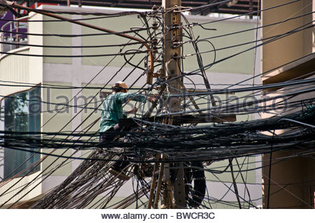Ein Thai Telefon-Ingenieur ein Kabel auf einen Telegrafenmast in einer ...