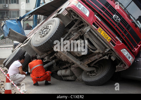 Ein LKW voll mit Sand beladen holt sich in ein Loch auf der Straße in ...