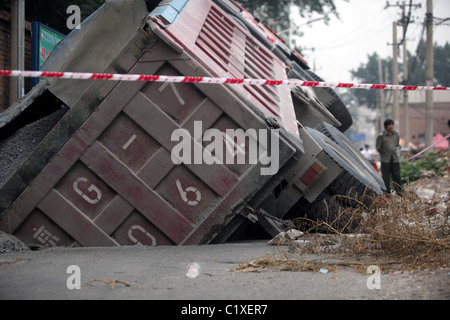 Ein LKW voll mit Sand beladen holt sich in ein Loch auf der Straße in ...