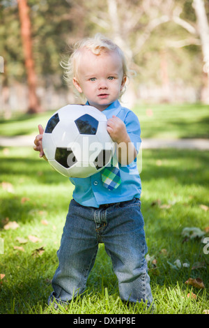 Glückliches Kleinkind mit einem Fußball auf rosa Studiohintergrund. Ein ...