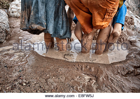 Zwei Mädchen im Schlamm stehen in der Nähe einer Toilette Bock auf dem ...