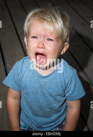 Baby weint. Ein junges Baby Junge weint, als er in seinen Hut Taufe ...