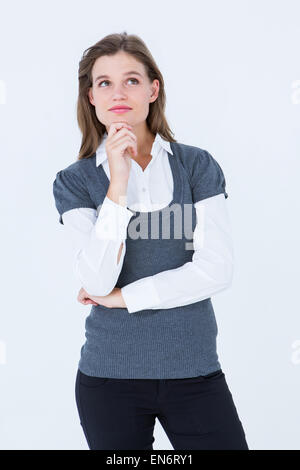 Blonde Frau mit Hand am Kinn und gefaltetem Arm im Atelier mit rosa ...