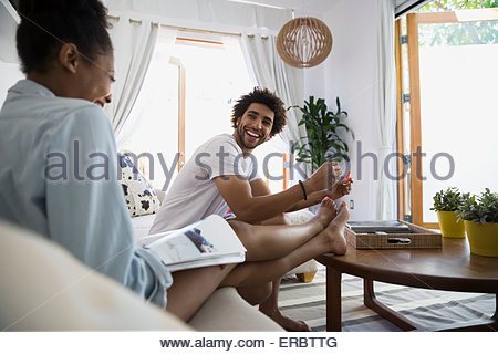 Barfuß-afroamerikanischer Mann in Pyjamahose, der auf dem Boden neben ...