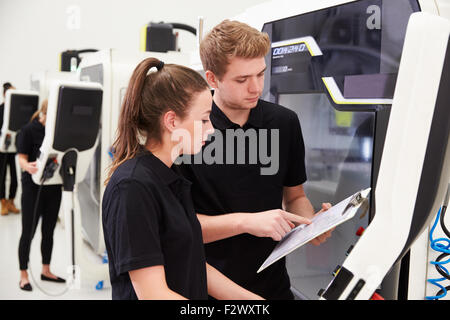Zwei junge Ingenieure, die Bedienung von CNC-Maschinen in Fabrikhalle ...