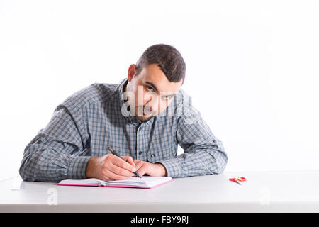 Der Junge schreibt zuhause Hausaufgaben in einem Notizbuch. Auf dem ...