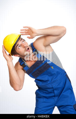 Bauarbeiter tragen blauen overall und grünen Helm posiert mit Schaufel ...
