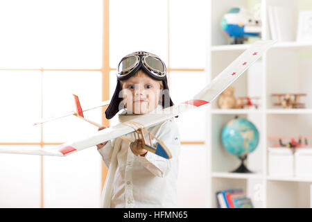 Kleiner Junge wie ein Pilot mit Spielzeugflügeln gegen den blauen ...