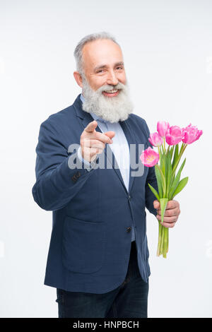Bärtiger Mann mit Blumenstrauß, der mit dem Finger nach vorne zeigt ...