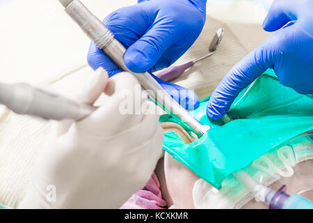 Ein Zahnarzt mit Dentalwerkzeugen bohrt die Zähne eines Patienten mit ...