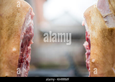 Tot Hausschwein hängt auf einem Gestell, während ein Metzger es offen ...