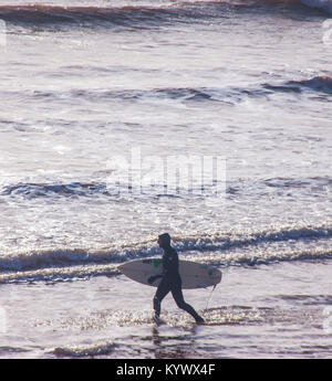 Sidmouth, 17. Jan 2018. Ein surfer Köpfe auf der Suche nach einer Welle ...