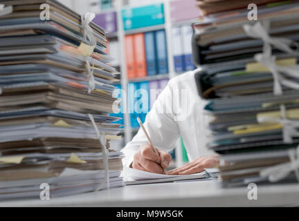 Stressigen Geschäftsmann im Büro mit zu viele Stapel von Papier und ...