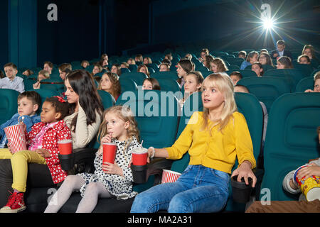Mitschüler aufpassen Film im Kino. Die Jungen und Mädchen auf der Suche glücklich, emotional ...