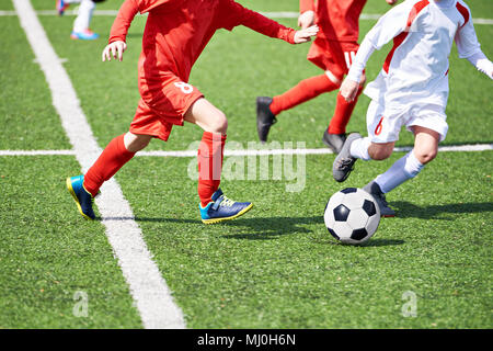 Kinder spielen auf dem Stadionfeld im Freien Fußball. Kinder erzielen ...