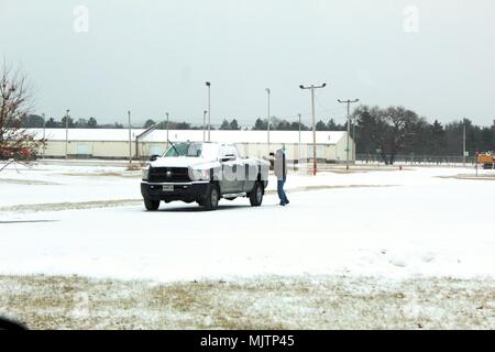 Eine Installation der Mitarbeiter beseitigt Schnee von einem Fahrzeuge ...