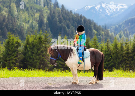 Kinder reiten Pony in den Alpen. Familie Frühling Ferien auf Horse ...