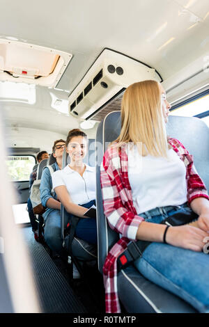 Happy Teen schoolgirl Riding School Bus mit Klassenkameraden und freuen ...