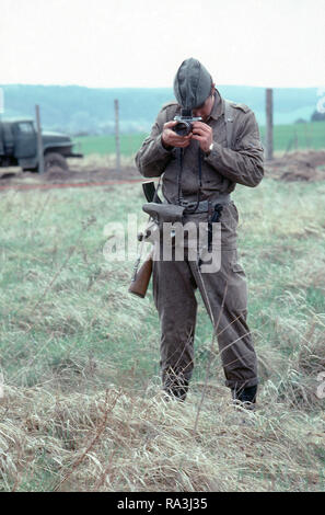 Ein bewaffneter Soldat DDR fotografiert entlang der Grenze zwischen Ost ...