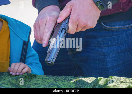 Pistole in die Hand eines Mannes auf einem Hintergrund von Rauch ...