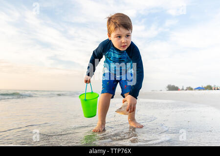 Kind am Strand spielen im Sand mit Eimer und Spaten Stockfotografie - Alamy