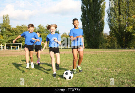 Kinder spielen auf dem Stadionfeld im Freien Fußball. Kinder erzielen ...