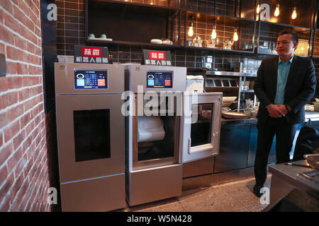 Ein chinesischer Mann betreibt einen Roboter Koch produziert von ...